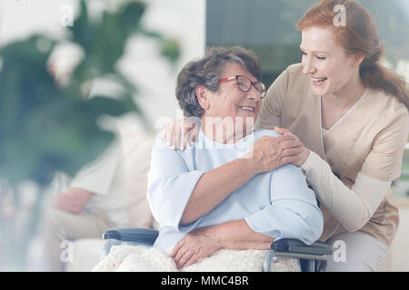 Happy patient is holding caregiver for a hand while spending time ...