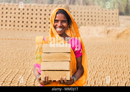 Female worker carrying bricks on her head at a brick making factory in ...