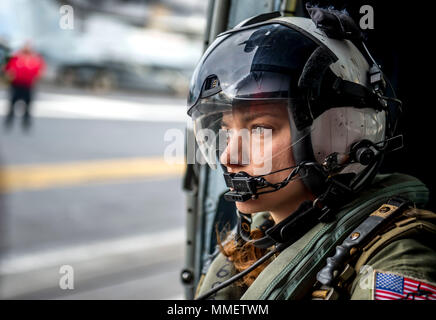 Naval Aircrewman looks out the door of an MH-60R Sea Hawk helicopter ...