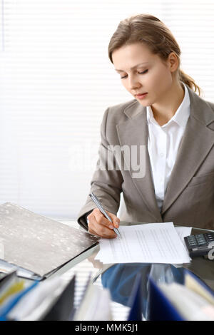 Portrait of female bookkeeper or financial inspector making report ...