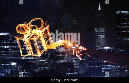 Glowing fire gift box icon in palm on dark background Stock Photo - Alamy