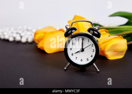 Black alarm clock near bouquet red tulips and red apple on black ...