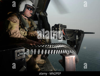 Naval Air Crewman mans a .50-caliber machine gun in an MH-60S Sea Hawk ...