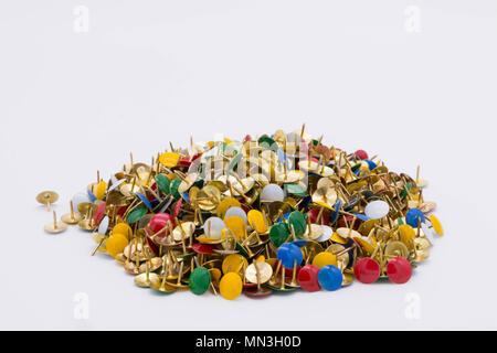 A pile of multicoloured drawing pins (thumb tacks) on a white ...