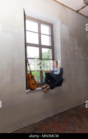 musician sitting next to a window with a classical guitar Stock Photo ...
