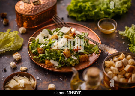 Plate of tasty Caesar salad and ingredients on color background Stock ...
