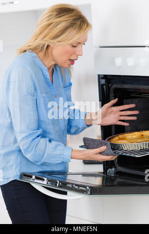 Woman removing pie from oven Stock Photo - Alamy