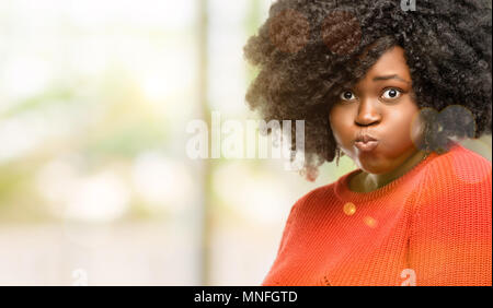 Beautiful african woman puffing out cheeks, having fun making funny ...