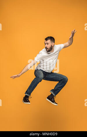 Freedom in moving. handsome young man jumping against orange background ...