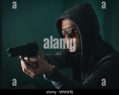 Hooded man with a gun in the dark Stock Photo - Alamy
