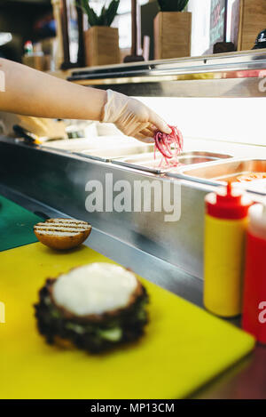 Male cook prepares fresh vegetables for burger. Hamburger preparation ...
