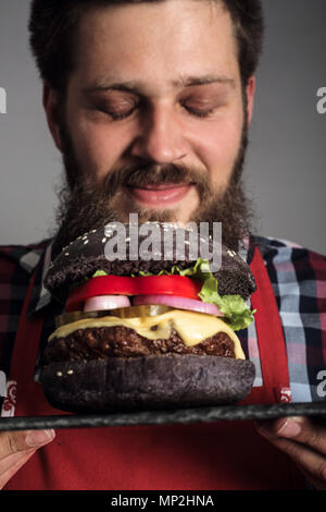 Man smelling fresh self made black burger close up Stock Photo - Alamy