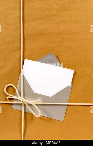 Brown paper parcel with silver envelope and blank message card Stock ...