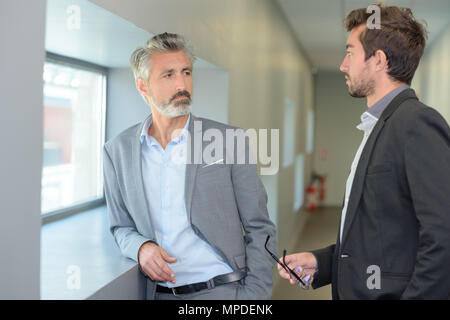 Two senior businessmen are having a serious conversation on their ...
