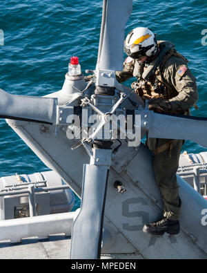 A Sailor conducts routine pre-flight checks on an MH-60 Sea Hawk ...