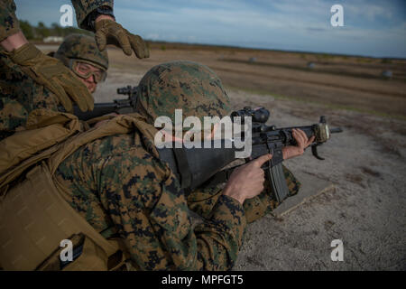 A Marine is corrected on his firing position and prone stance by a ...