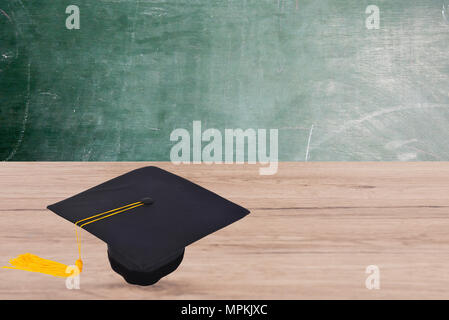 Graduated cap placed on a wooden desk in the classroom Stock Photo - Alamy