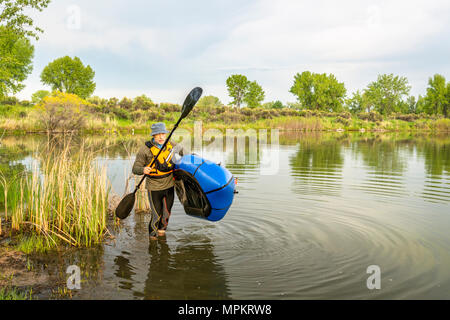 senior male carrying a packraft (one-person light raft used for ...