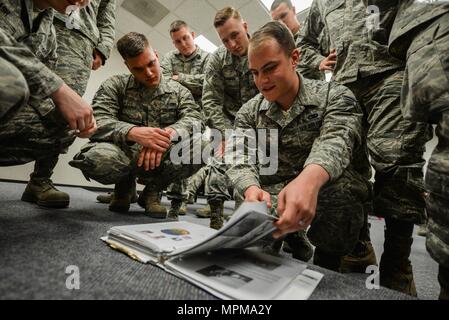 Airmen huddle around a binder full of Air Force heritage pictures and ...