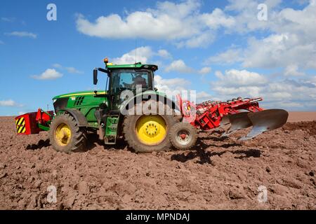 man using tractor and ridging machine to prepare furrows for ...