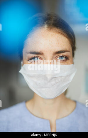 Young woman wearing surgical mask with arms folded isolated over purple ...
