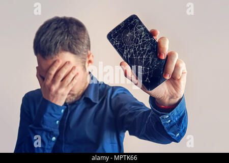 Angry man holding crashed mobile phone on the street Stock Photo - Alamy