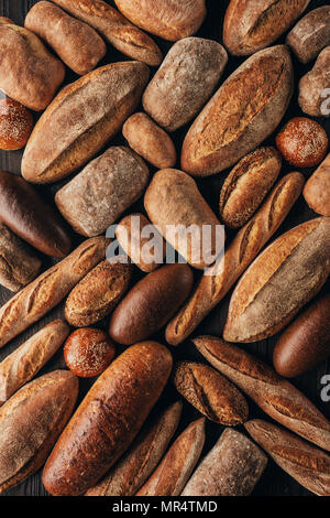 top view of arranged loafs of bread in wooden box on dark tabletop with ...