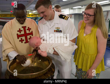 A US Navy Chaplain baptizes a US Navy Officer in a ceremony of baptism ...