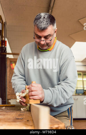 Experienced carpenter planing a board Stock Photo - Alamy