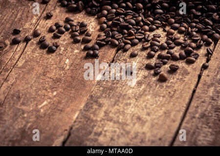 Close-up view of spilled fresh coffee beans on wooden table background ...