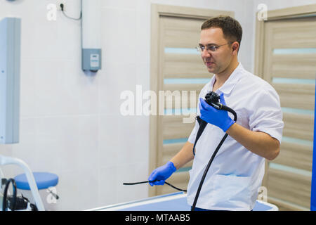 Proctologist holding an anoscope against a proctological chair. In the ...