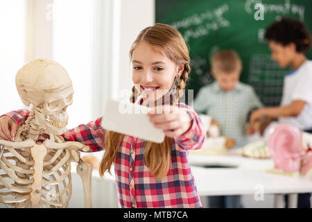 Photo of cheerful positive learner girl sit floor read book toothy ...