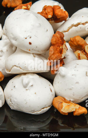 Meringue with nuts on a black plate. Macro mode. Cane sugar. Candy ...