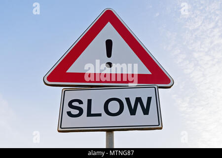 slow down red triangle road sign traffic calming measures blue sky ...