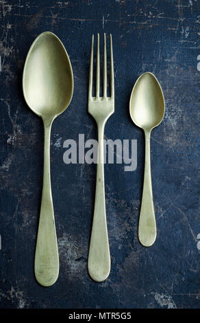 Golden spoons and fork over dark grunge background, top view Stock ...