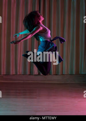 Modern style dancer jumping in studio on black background. Beautiful ...