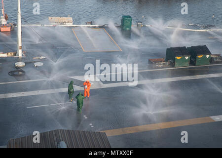 Sailors test sprinklers on the flight deck during a counter measure ...