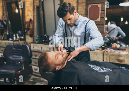 Male barber trimming customers beard in barber shop Stock Photo - Alamy