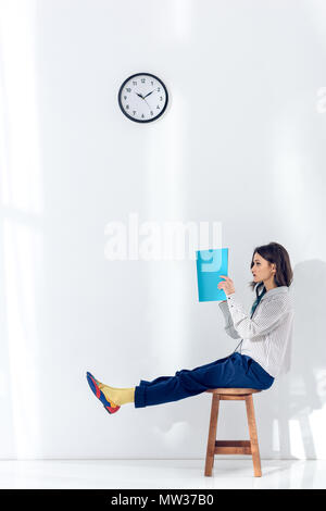 Young attractive woman under the clock, on blue background Stock Photo ...