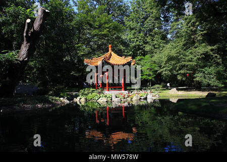 A Chinese style alcove near the pond in a public park with people ...