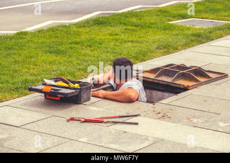 Working in manhole, worker making repairs on water supply at city ...