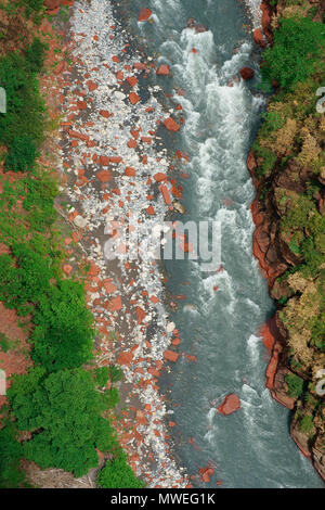 Aerial view of red, eroded canyon landscape with sparse green ...