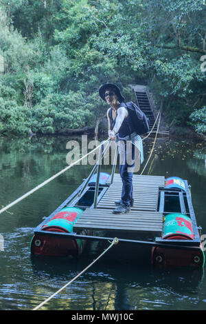 Mature female adventurer on the pontoon crossing in wilderness national ...