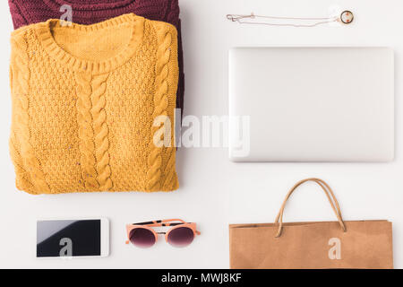 flat lay with knitted sweaters, sunglasses, laptop, smartphone ...