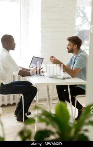Diverse colleagues discussing work. A black employee explaining new job ...