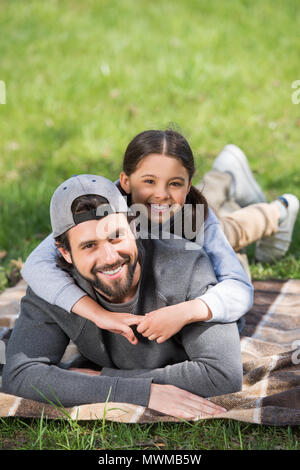 Father laying on his back in the grass with her young daughter ...