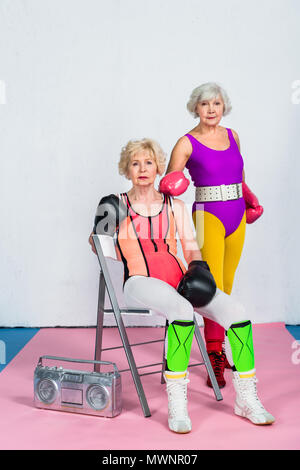 An old senior women boxing in red gloves, looking aggressively funny ...