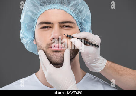 doctor drawing lines for facelifting on man, isolated on grey Stock ...