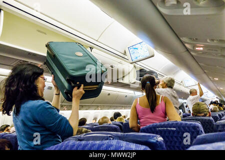 Passengers stowing luggage in overhead lockers Boeing 737 aircraft and ...