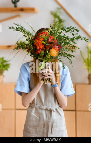 Young florist hiding behind beautiful bouquet on grey background Stock ...